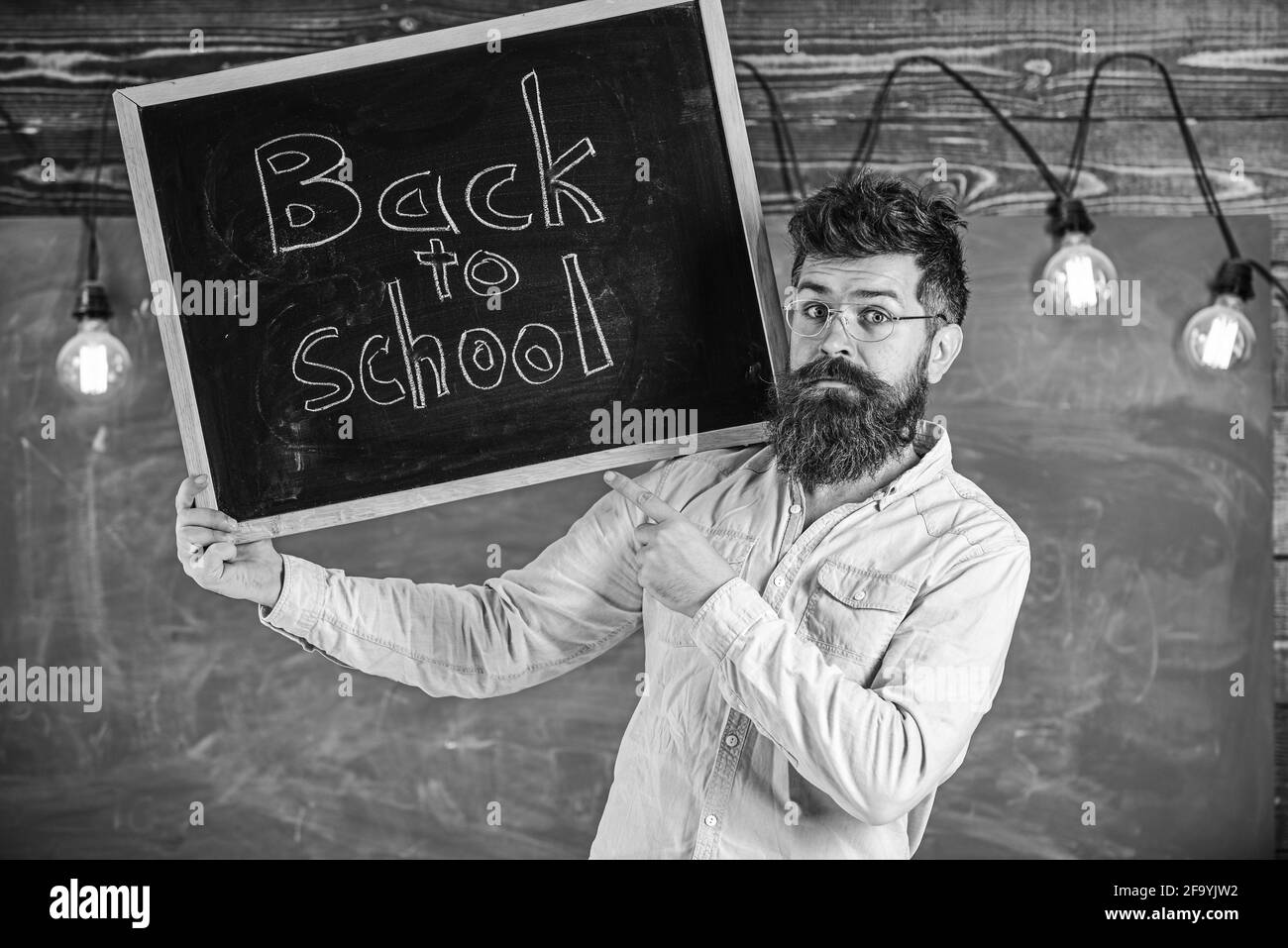 Teacher in eyeglasses holds blackboard with title back to school. High ...
