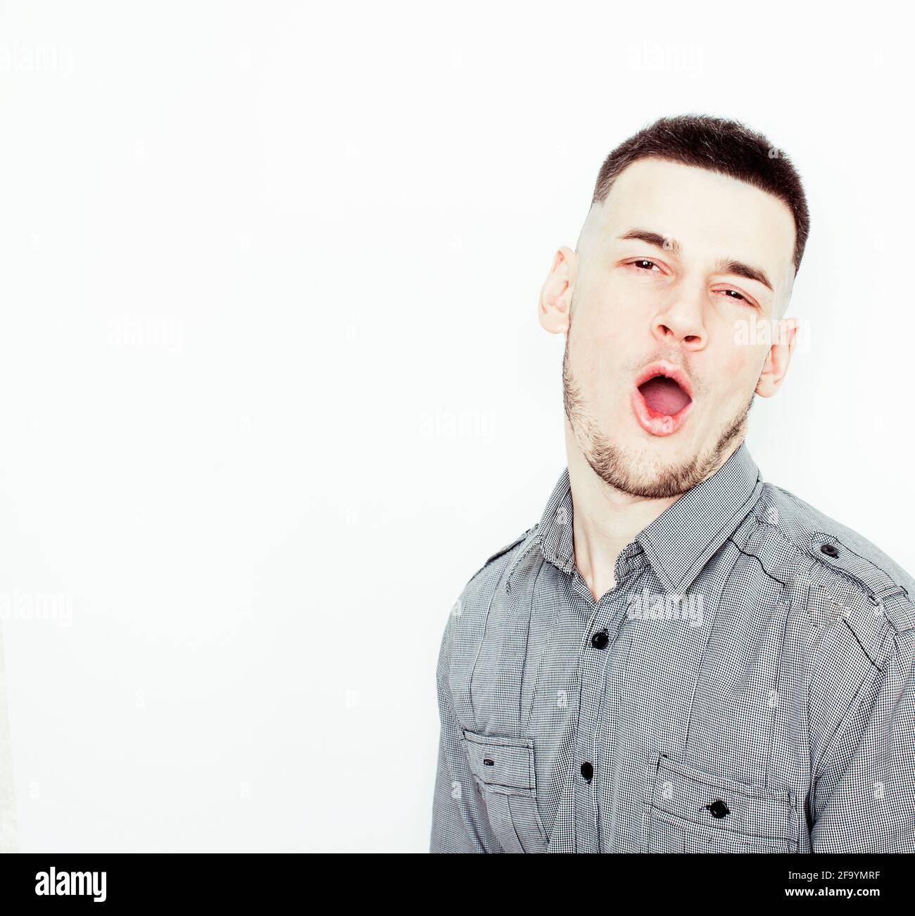 Portrait of a smart serious young man standing against white background ...