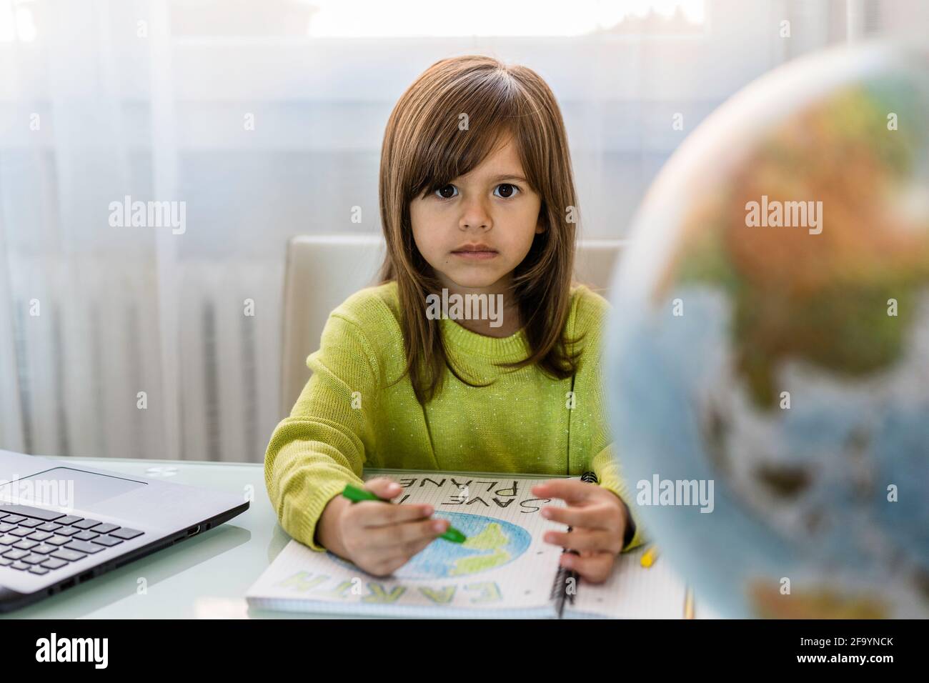 Worried child girl draws planet earth with wax colors on school ...