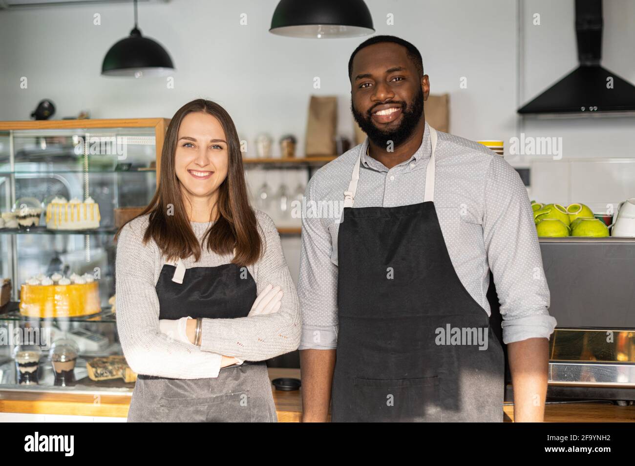 Smiling caucasian waitress and cheerful African-American waiter stands ...