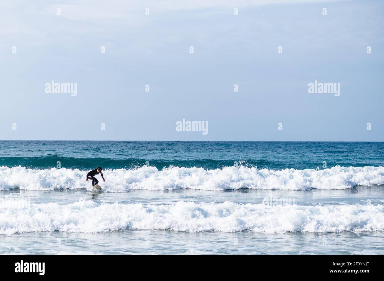 Surfer riding a wave at distance Stock Photo - Alamy
