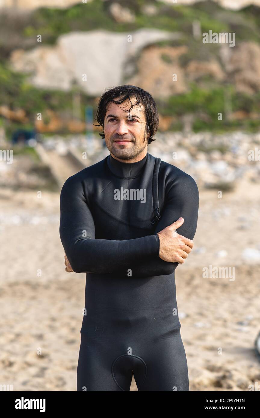 Medium shot young wet man wearing diving suit standing on the beach ...