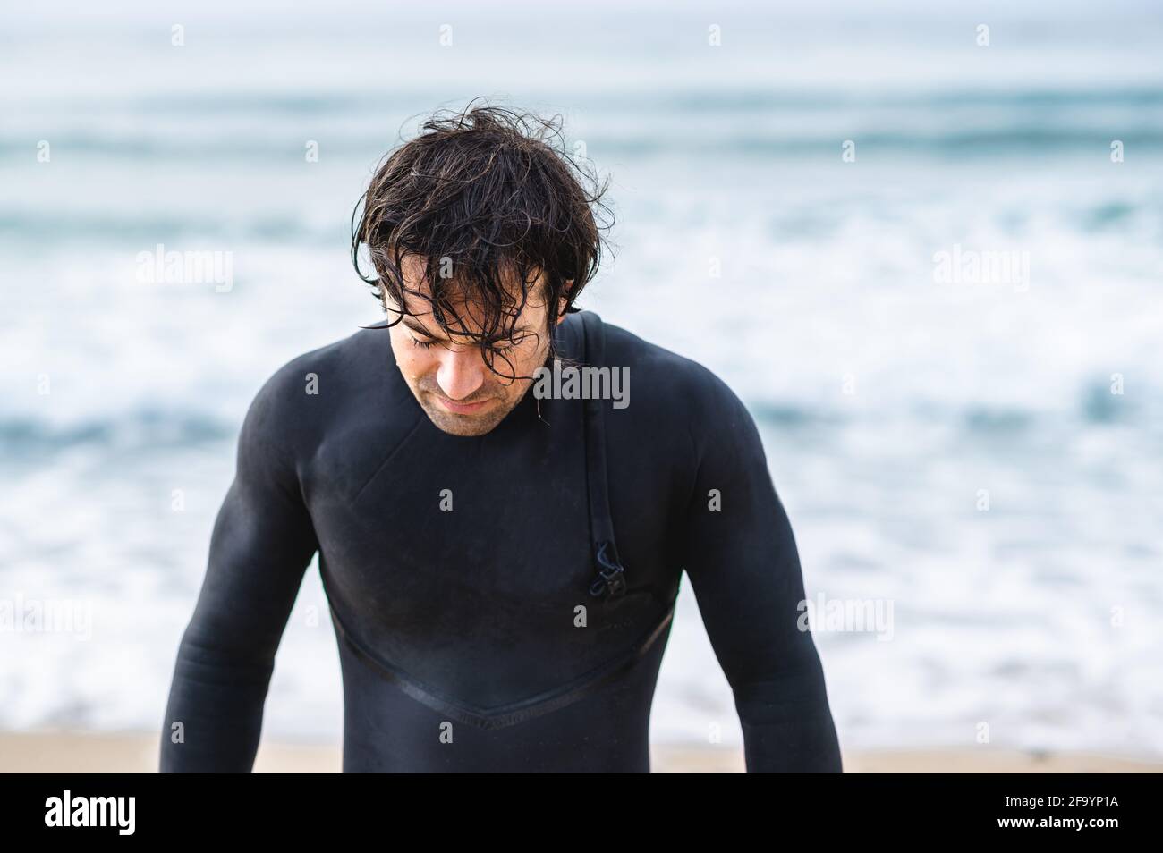 Medium shot young wet man with diving suit getting out of the sea ...