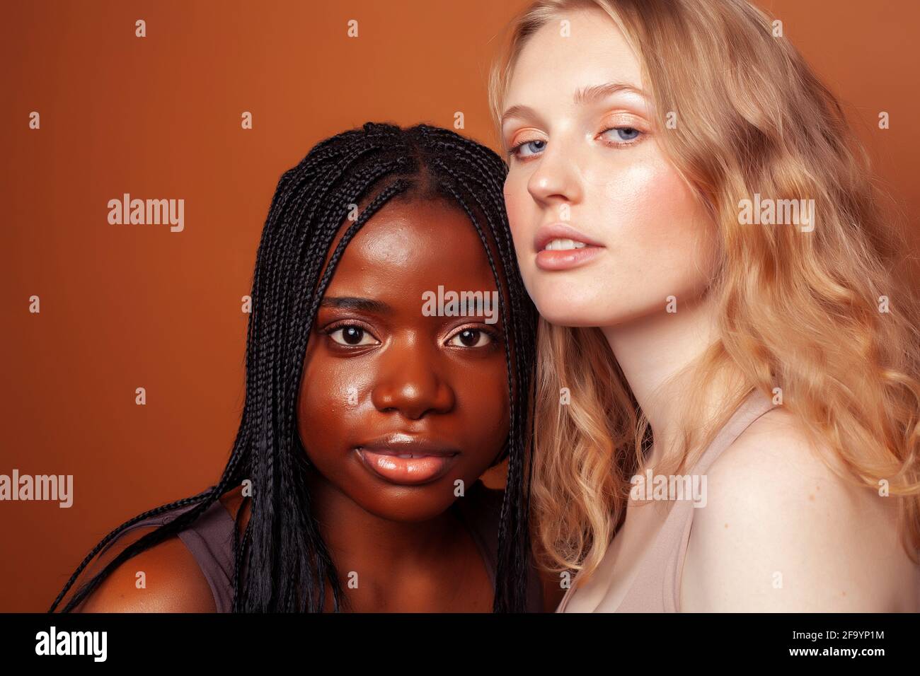 two pretty girls african and caucasian blond posing cheerful together ...