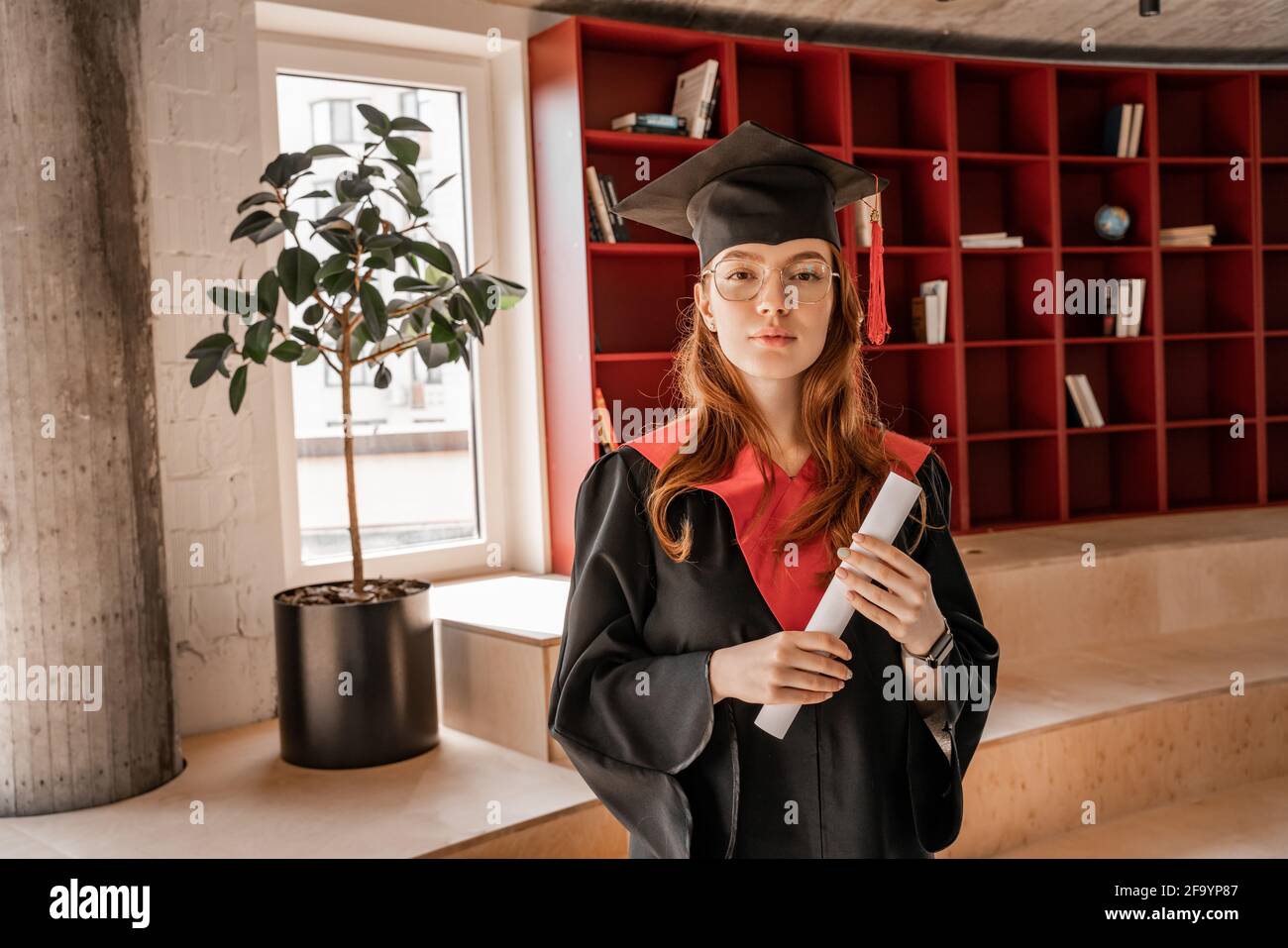 redhead student in graduation cap and gown holding diploma Stock Photo ...