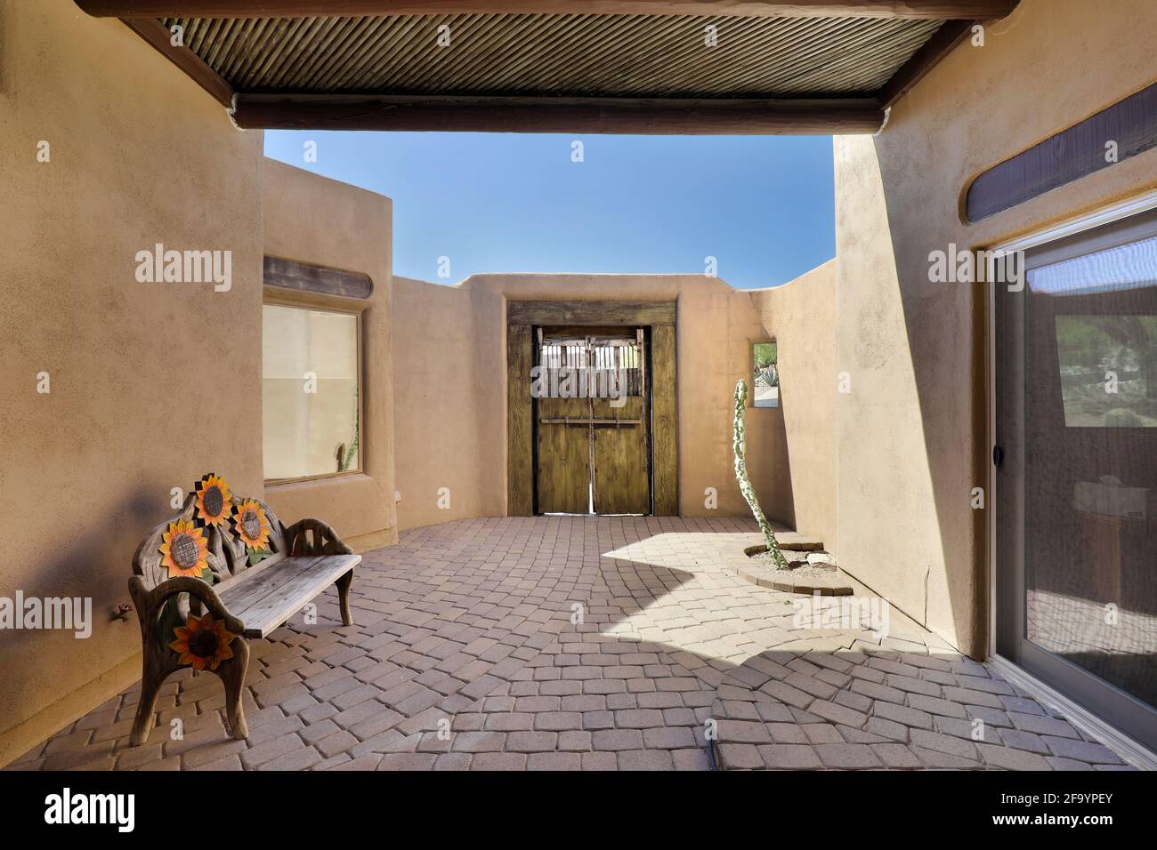 Courtyard with adobe walls and brick paving with wooden doors in a ...