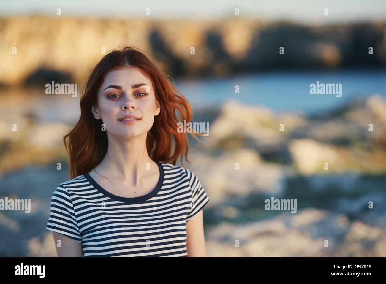 red-haired traveler in mountains outdoors in striped t-shirt cropped ...
