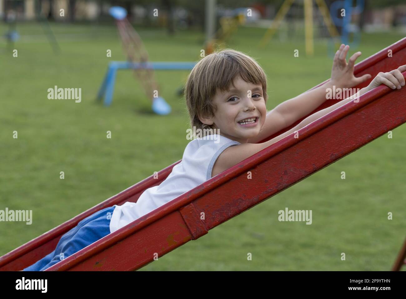 Shallow focus shot of a cheerful Caucasian boy on a slide in the ...