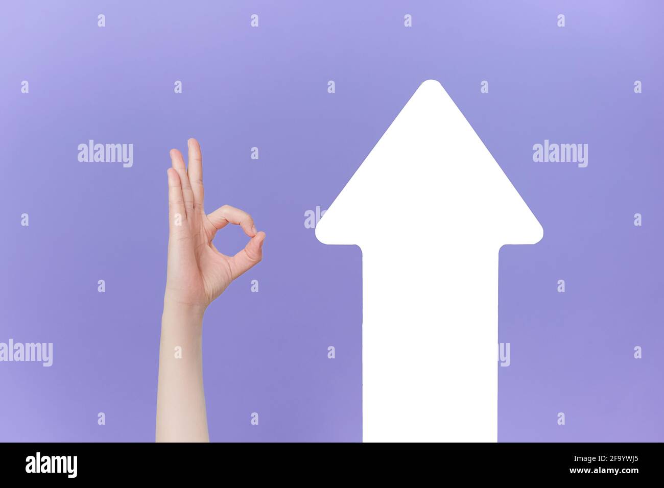 Unrecognizable young male makes thumb up gesture near white paper arrow ...