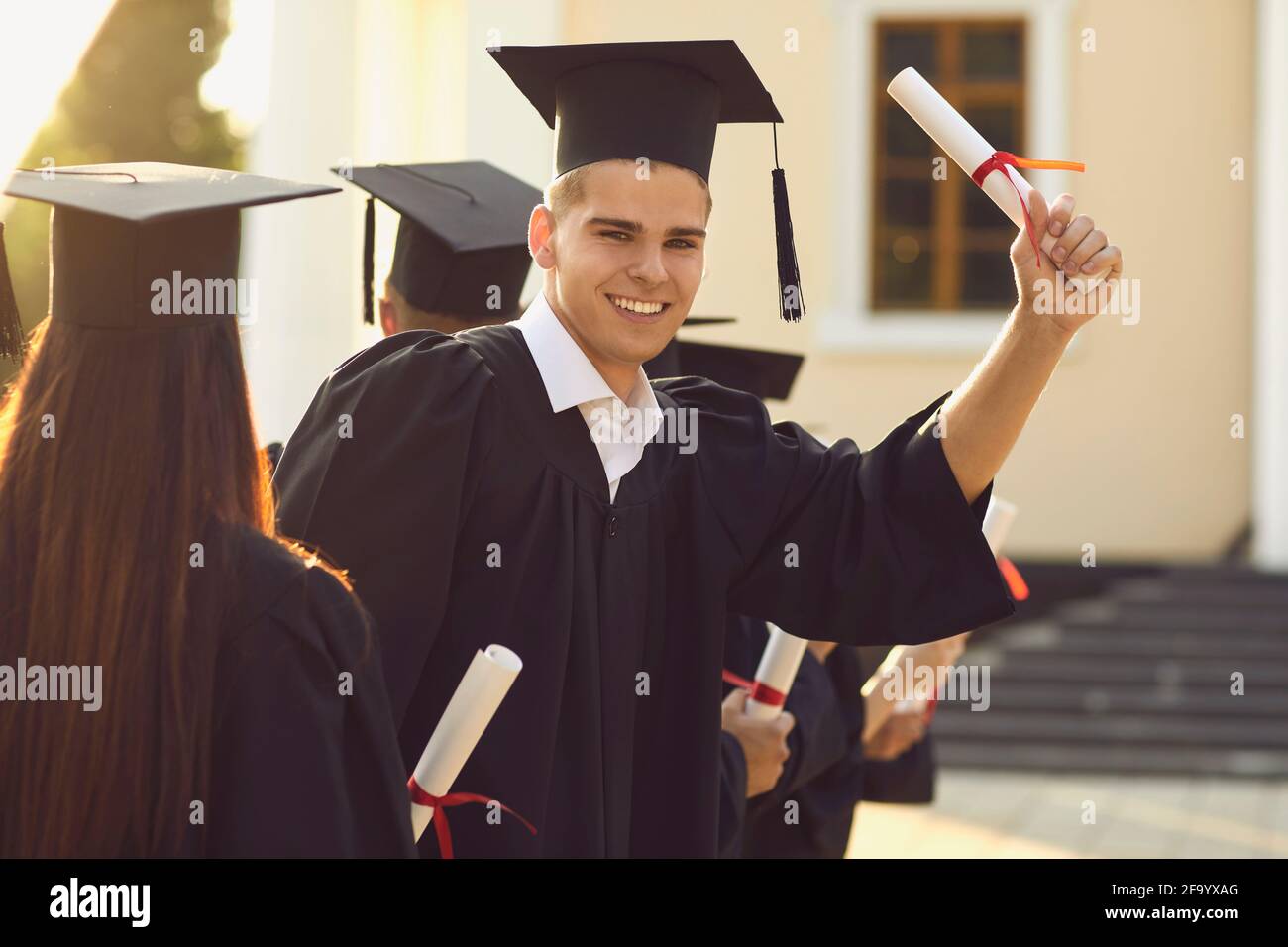 Smiling happy university graduate holding diploma in raised hand Stock ...