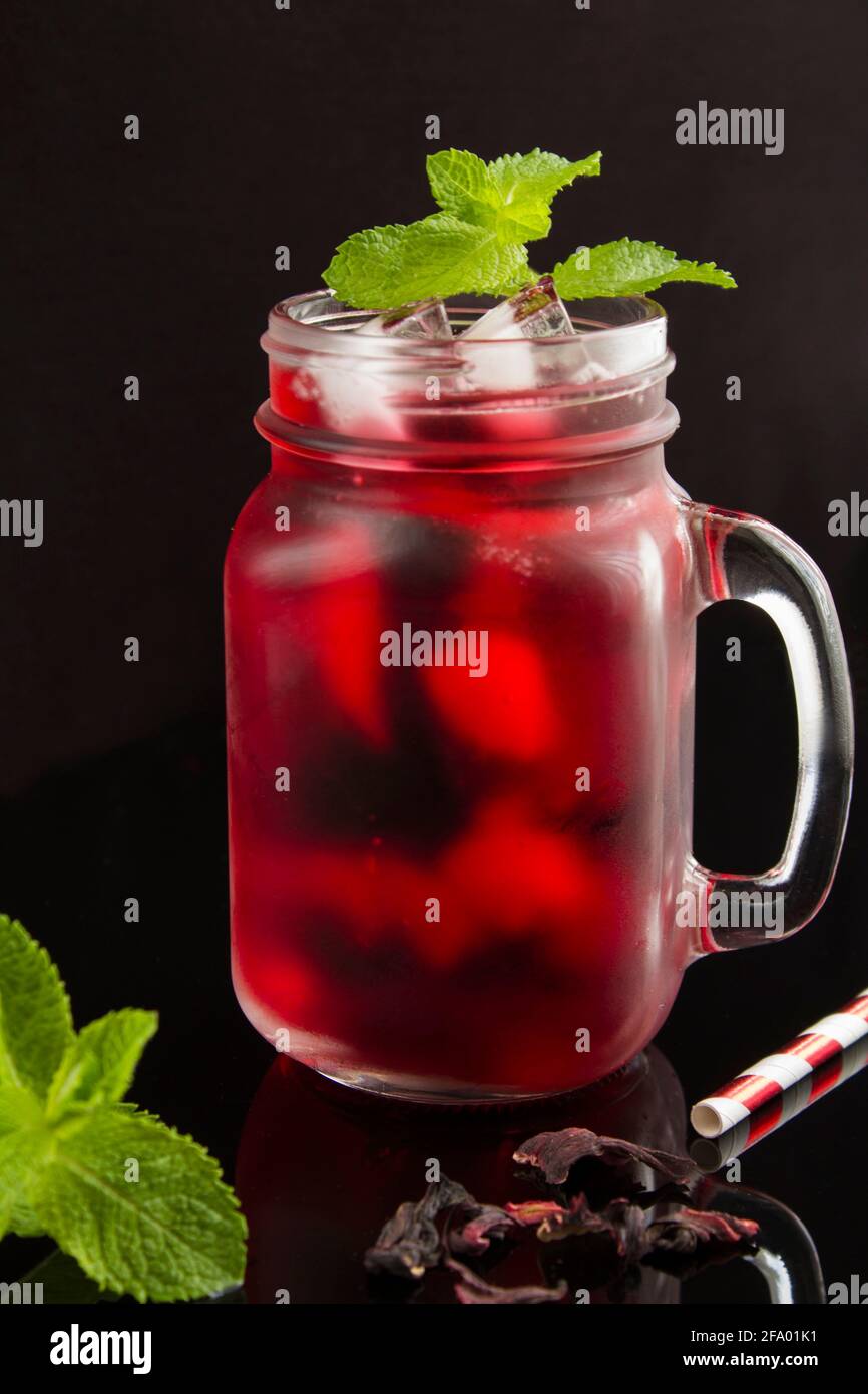 Iced hibiscus or karkade tea in the glass on the black background ...