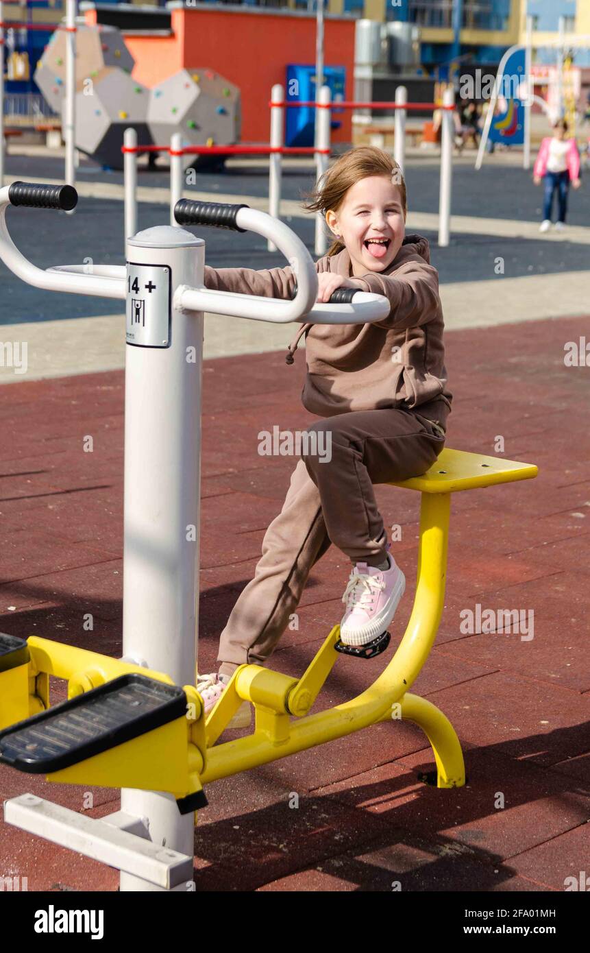 Adorable little kid girl making exercises on sports training apparatus ...