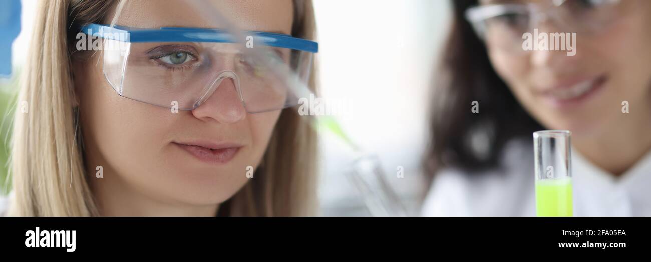 Female scientists pouring chemical liquid from pipette into test tube ...