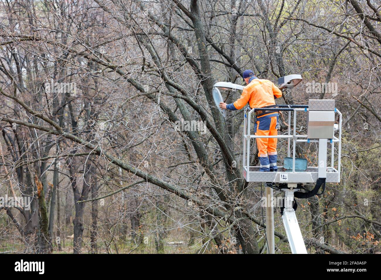 A utility worker in an orange uniform uses a construction hoist to ...