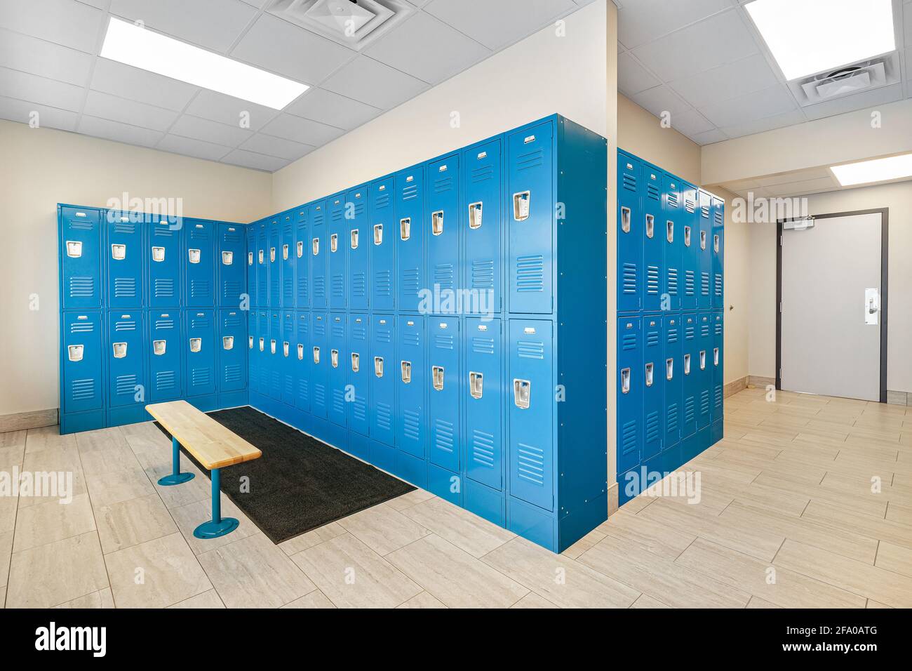A clean locker room with bright blue lockers and a bench mounted to the ...