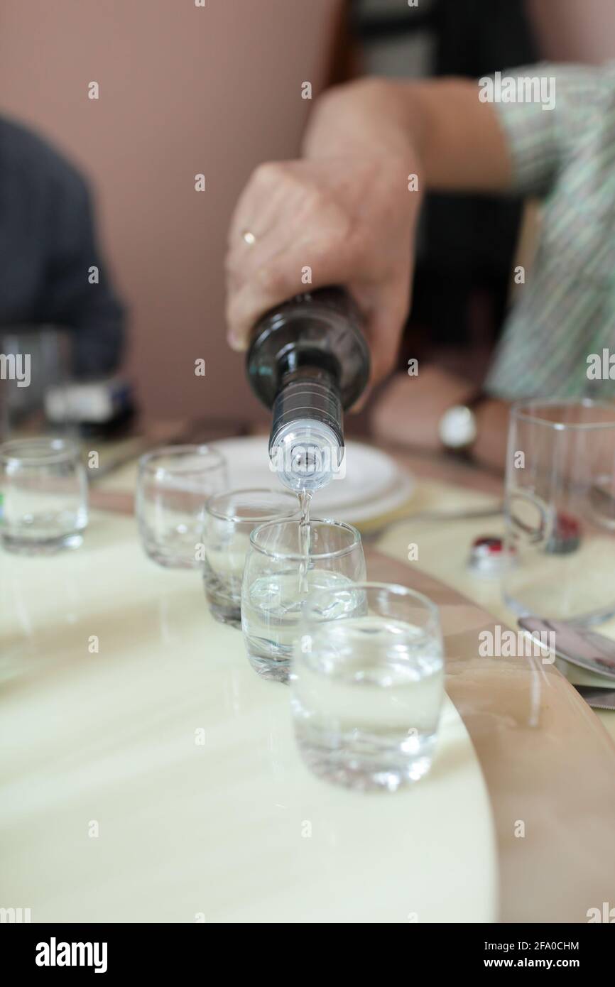 Man pours vodka from bottle into drinking glasses Stock Photo - Alamy