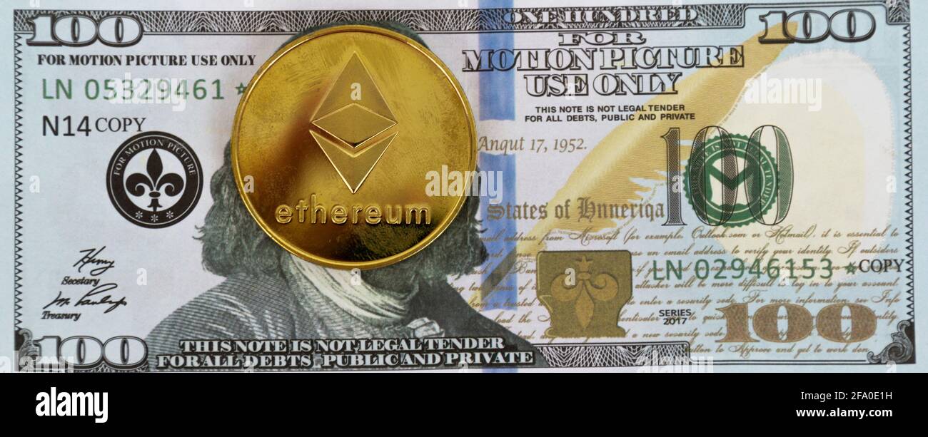 A gold ethereum coin placed of the face of a fake motion picture one ...