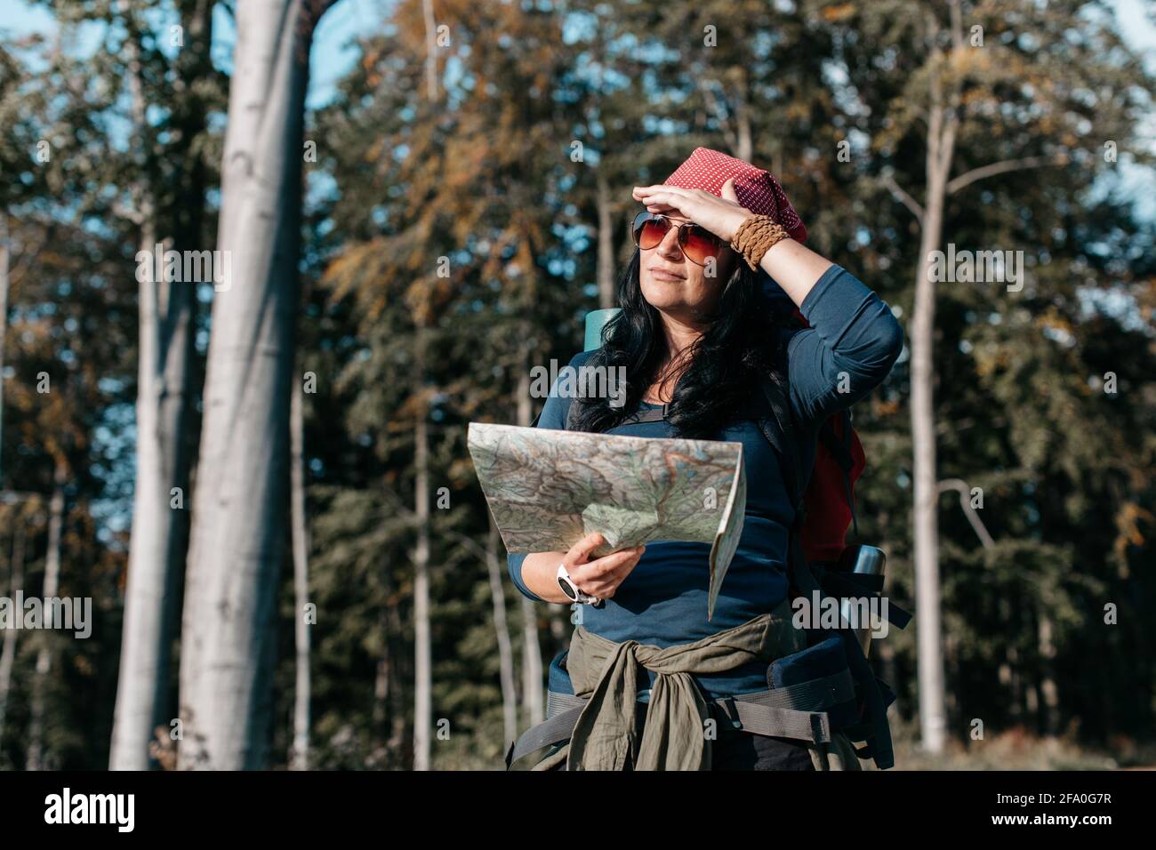A woman with a backpack checking a map. A female hiker hiking in the ...