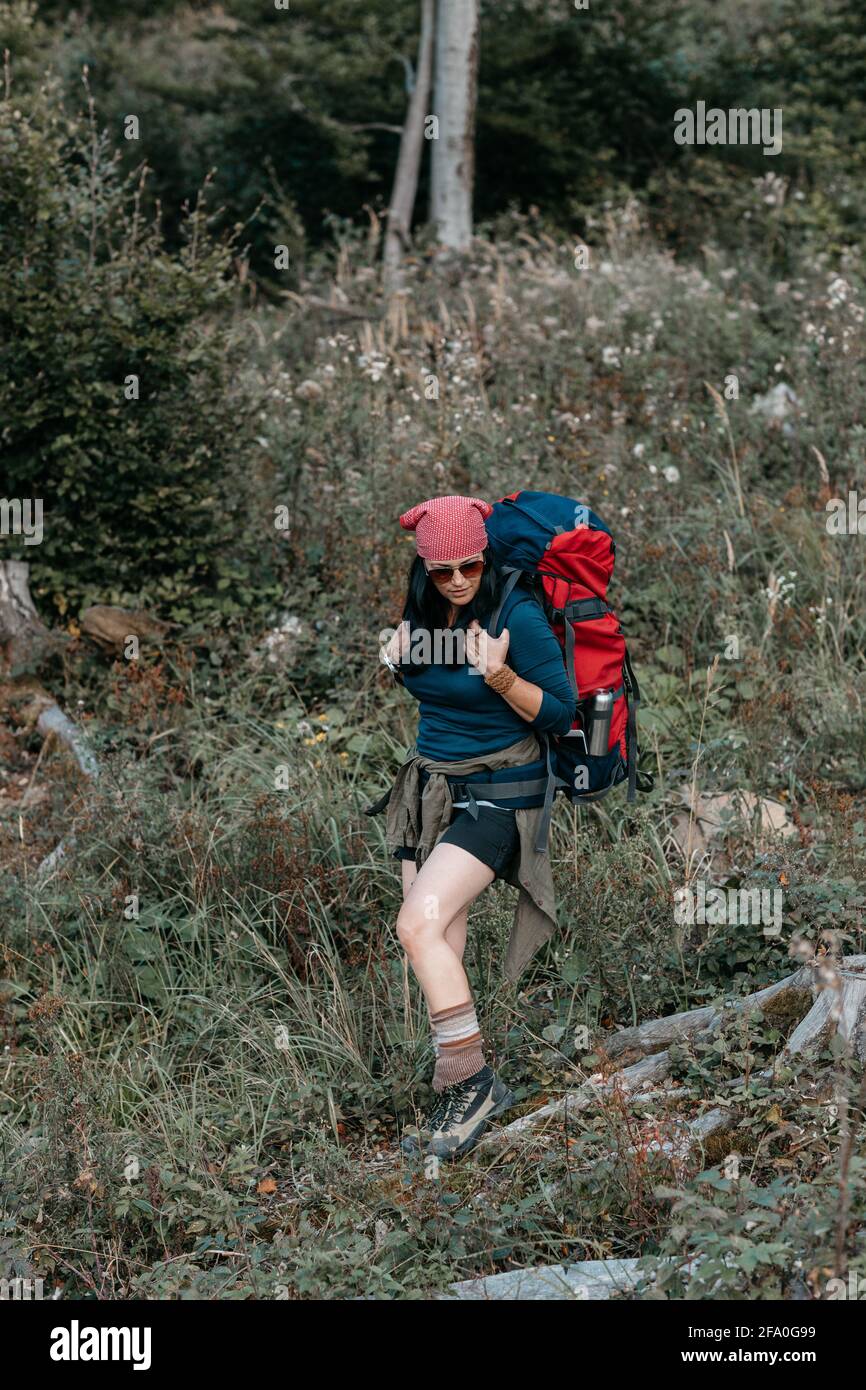 A woman hiking alone in the woods. A female tourist walking through ...