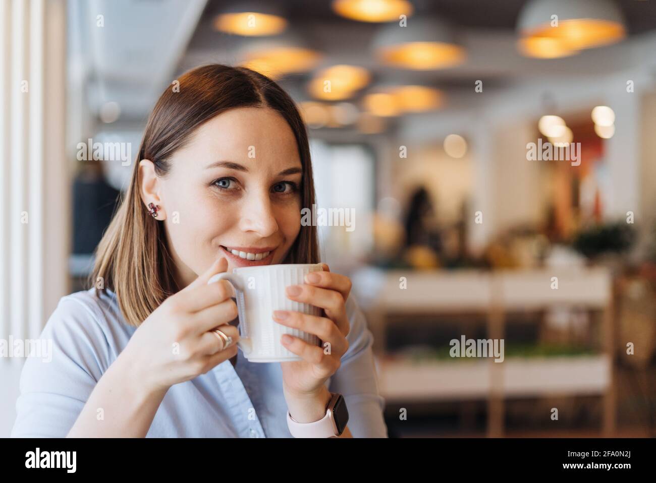 Attractive female with cute smile having a coffee while relaxin in a ...