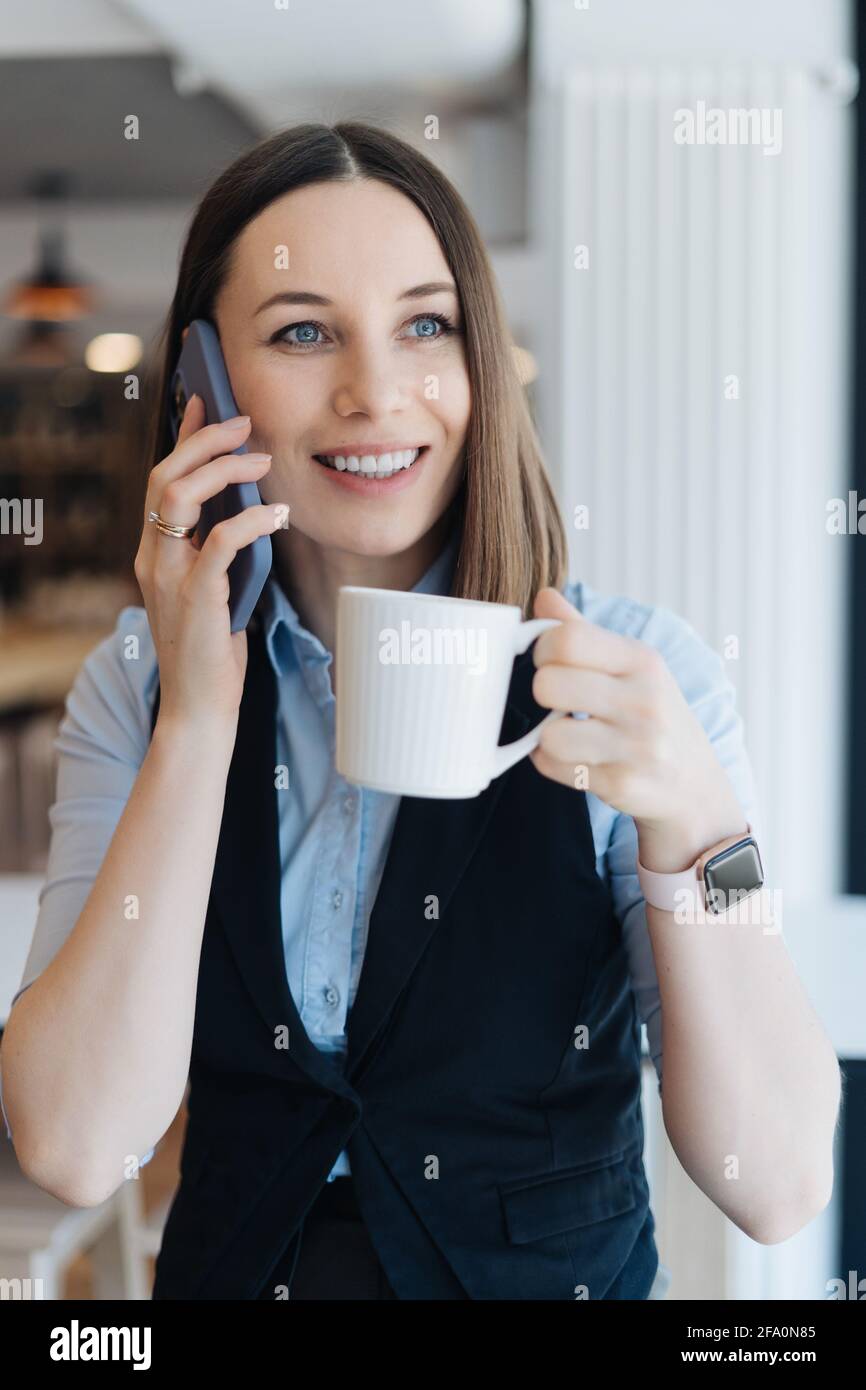 Young charming woman calling with smartphone while sitting alone in ...