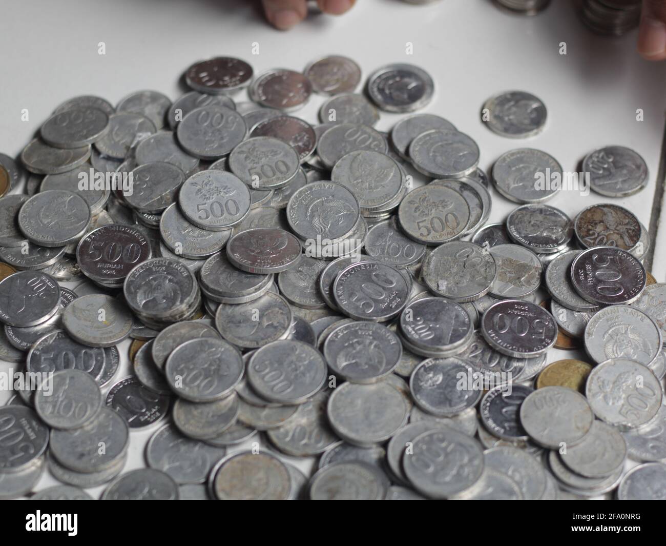 Man counting indonesian penny. Stacked Rupiah coin Stock Photo - Alamy