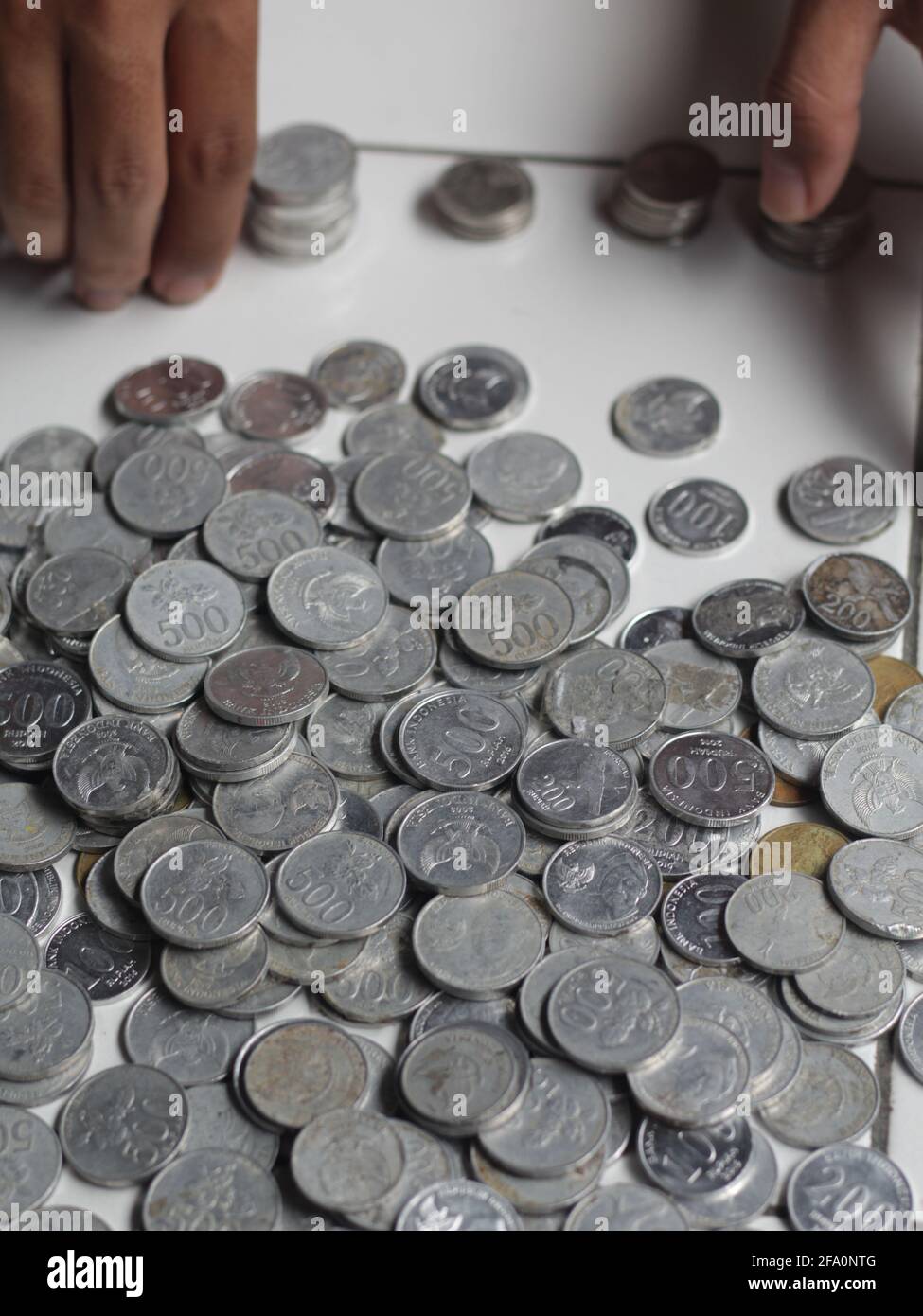 Man counting indonesian penny. Stacked Rupiah coin Stock Photo - Alamy
