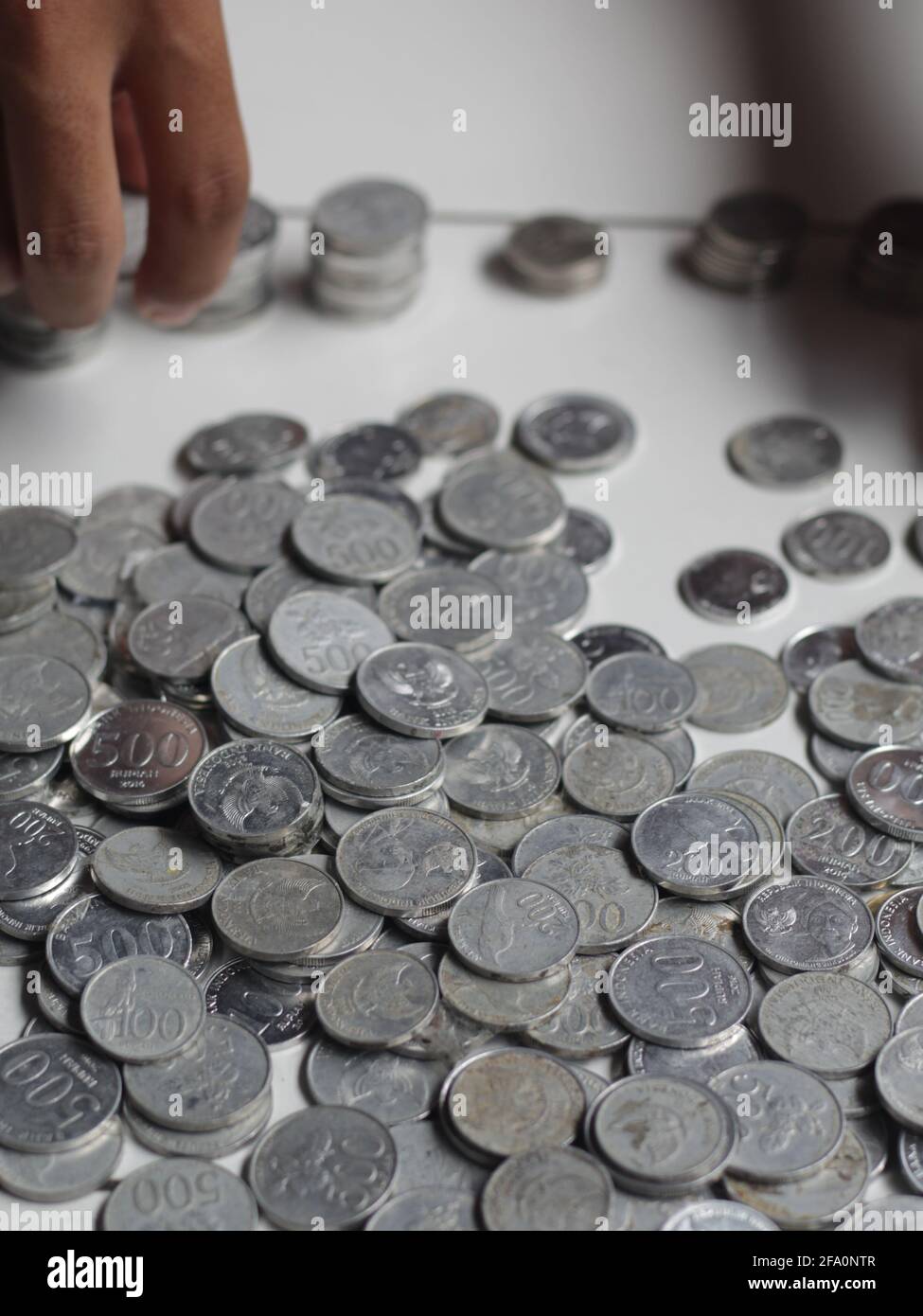 Man counting indonesian penny. Stacked Rupiah coin Stock Photo - Alamy