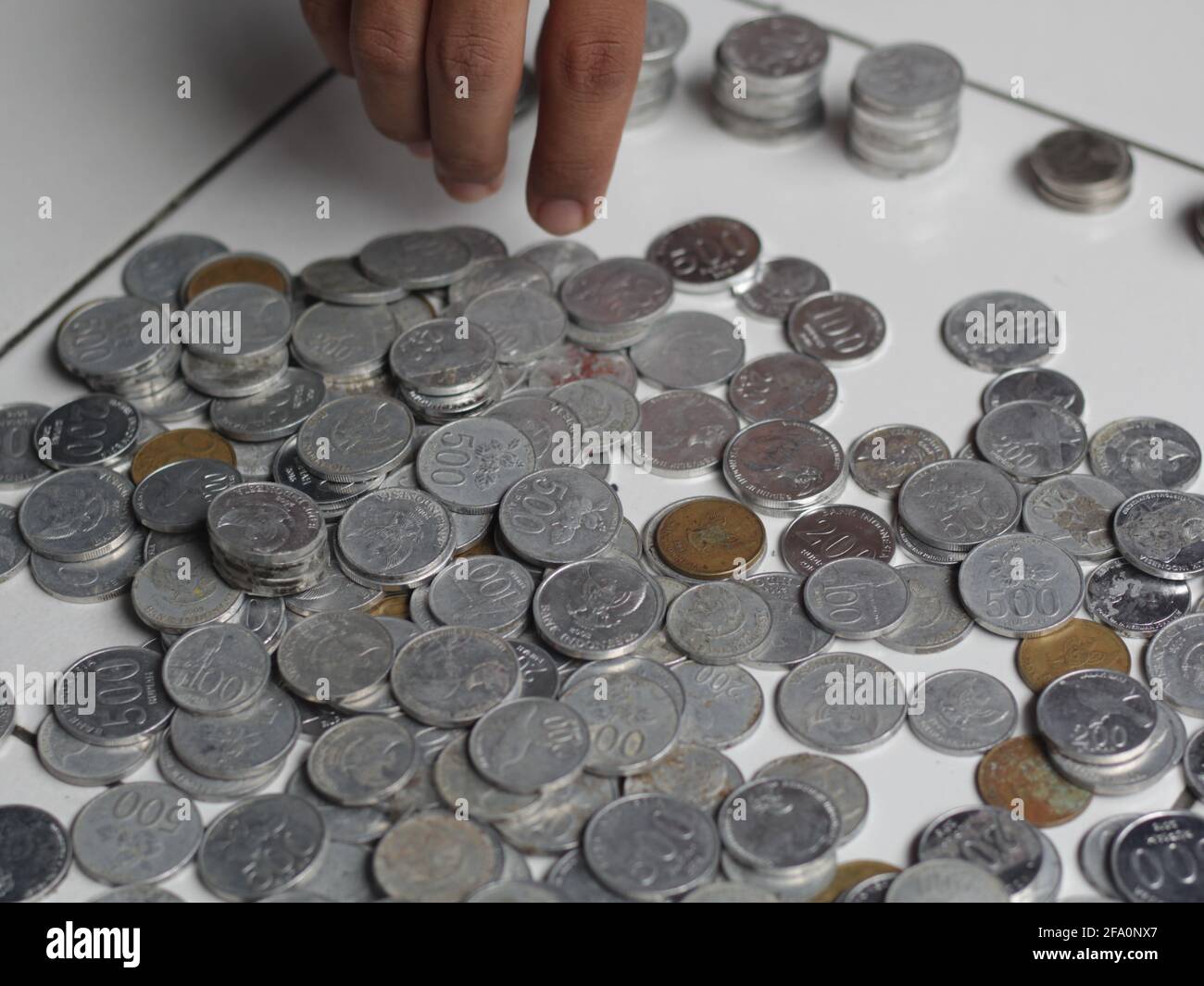 Man counting indonesian penny. Stacked Rupiah coin Stock Photo - Alamy