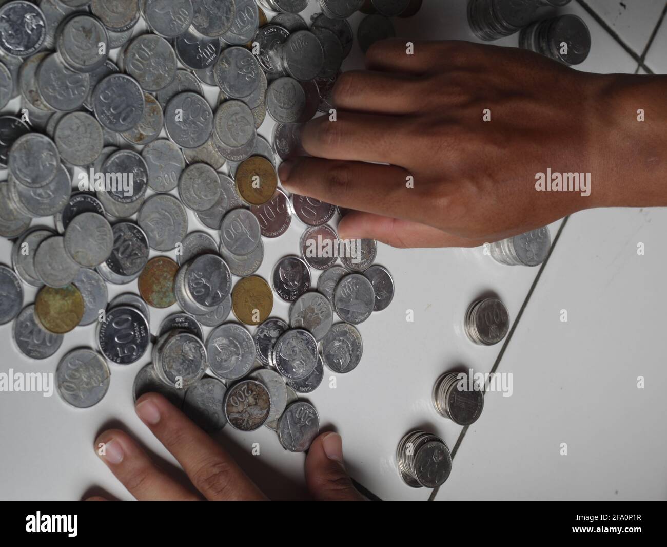 Man counting indonesian penny. Stacked Rupiah coin Stock Photo - Alamy