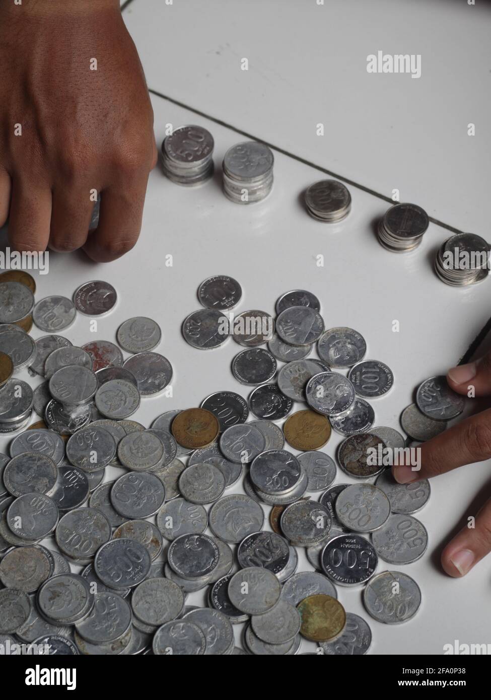 Man counting indonesian penny. Stacked Rupiah coin Stock Photo - Alamy