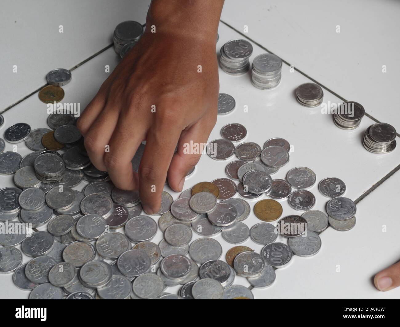 Man counting indonesian penny. Stacked Rupiah coin Stock Photo - Alamy