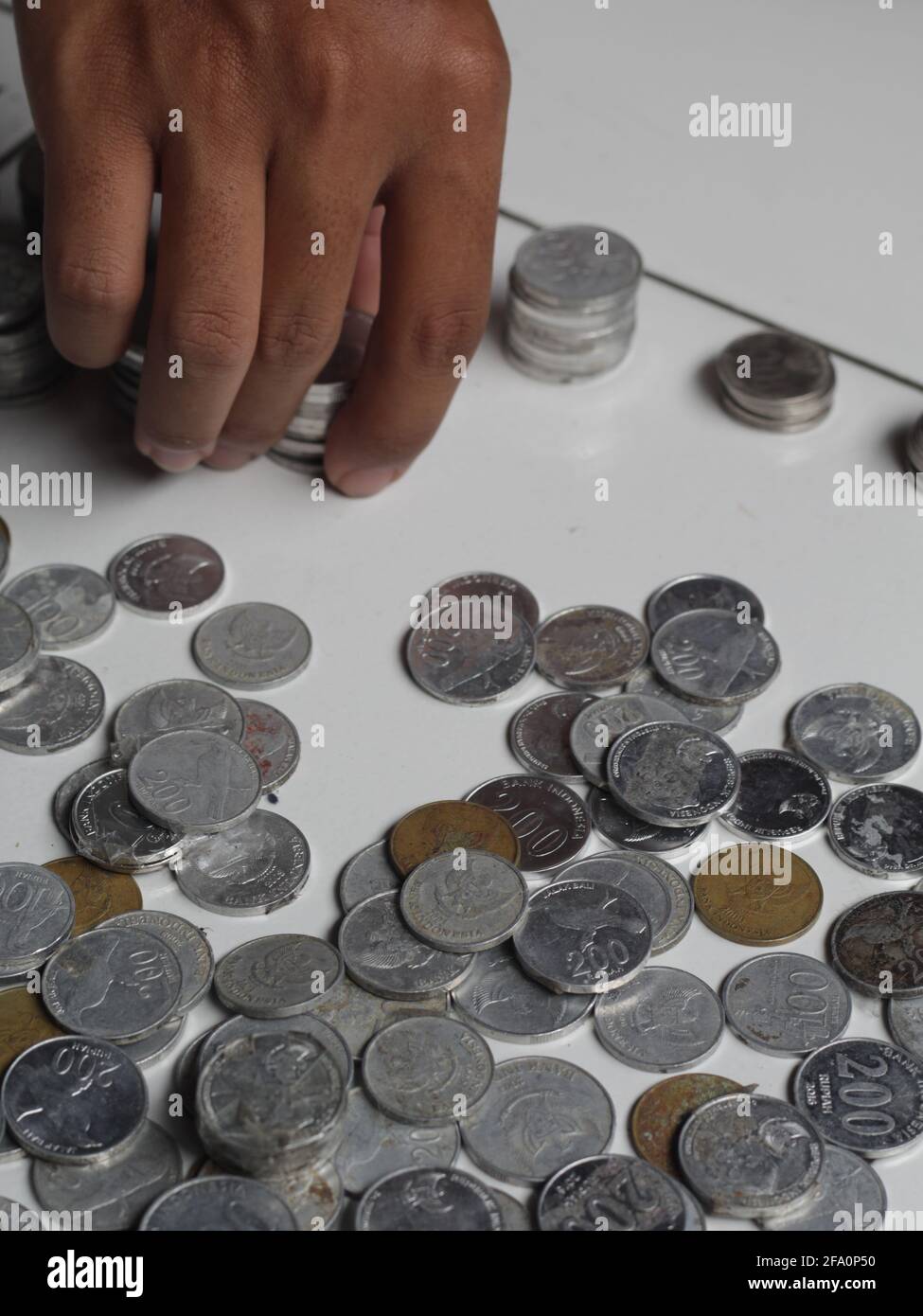 Man counting indonesian penny. Stacked Rupiah coin Stock Photo - Alamy