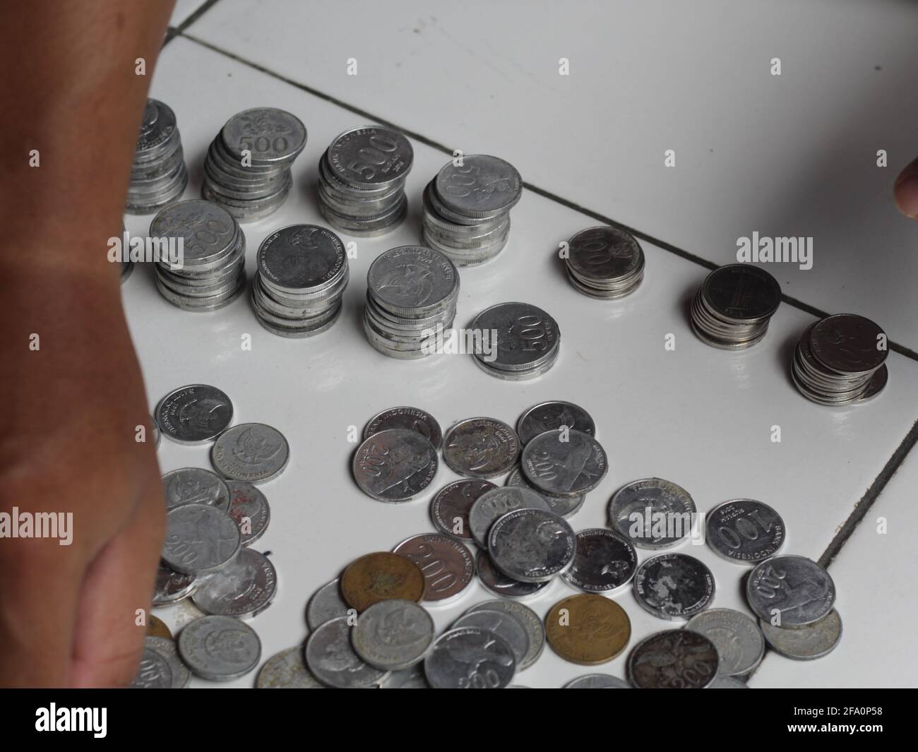 Man counting indonesian penny. Stacked Rupiah coin Stock Photo - Alamy