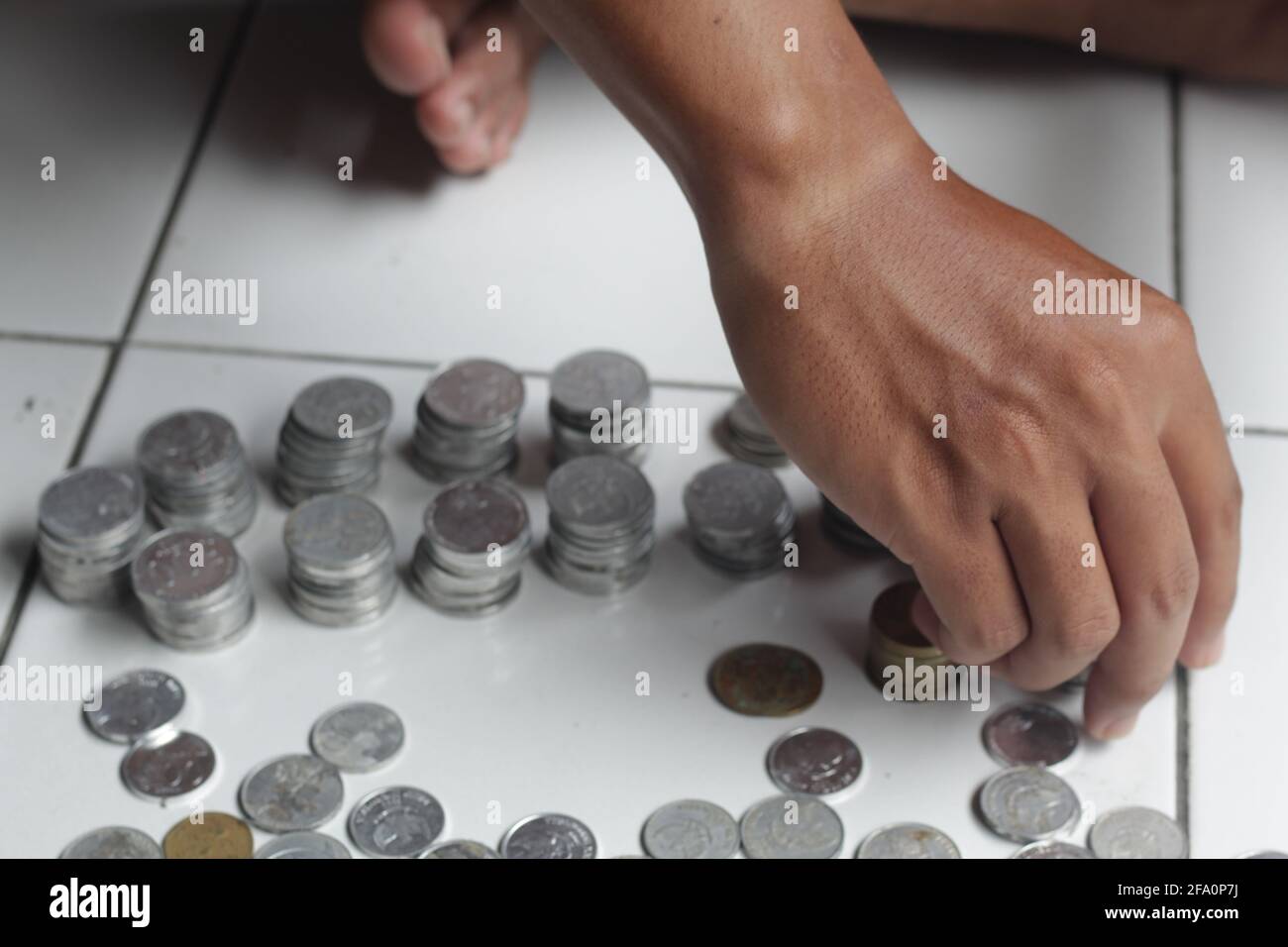 Man counting indonesian penny. Stacked Rupiah coin Stock Photo - Alamy