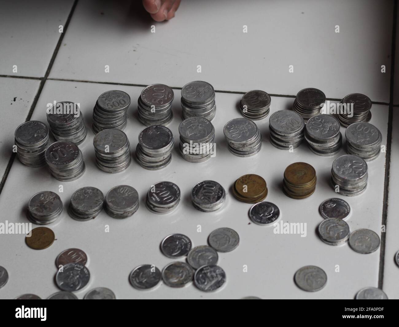 Man counting indonesian penny. Stacked Rupiah coin Stock Photo - Alamy