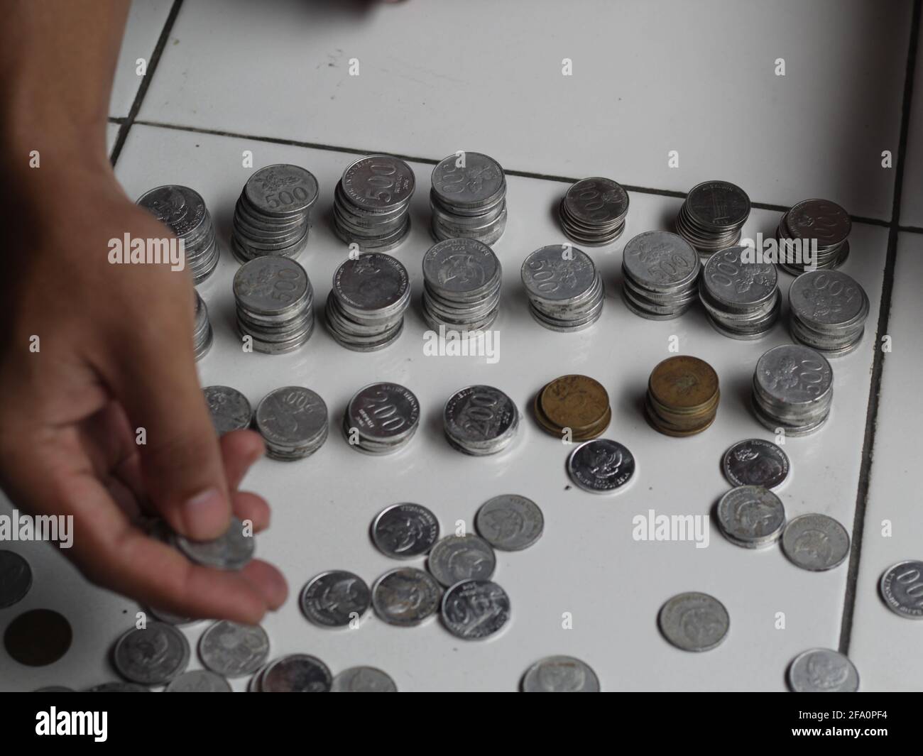 Man counting indonesian penny. Stacked Rupiah coin Stock Photo - Alamy