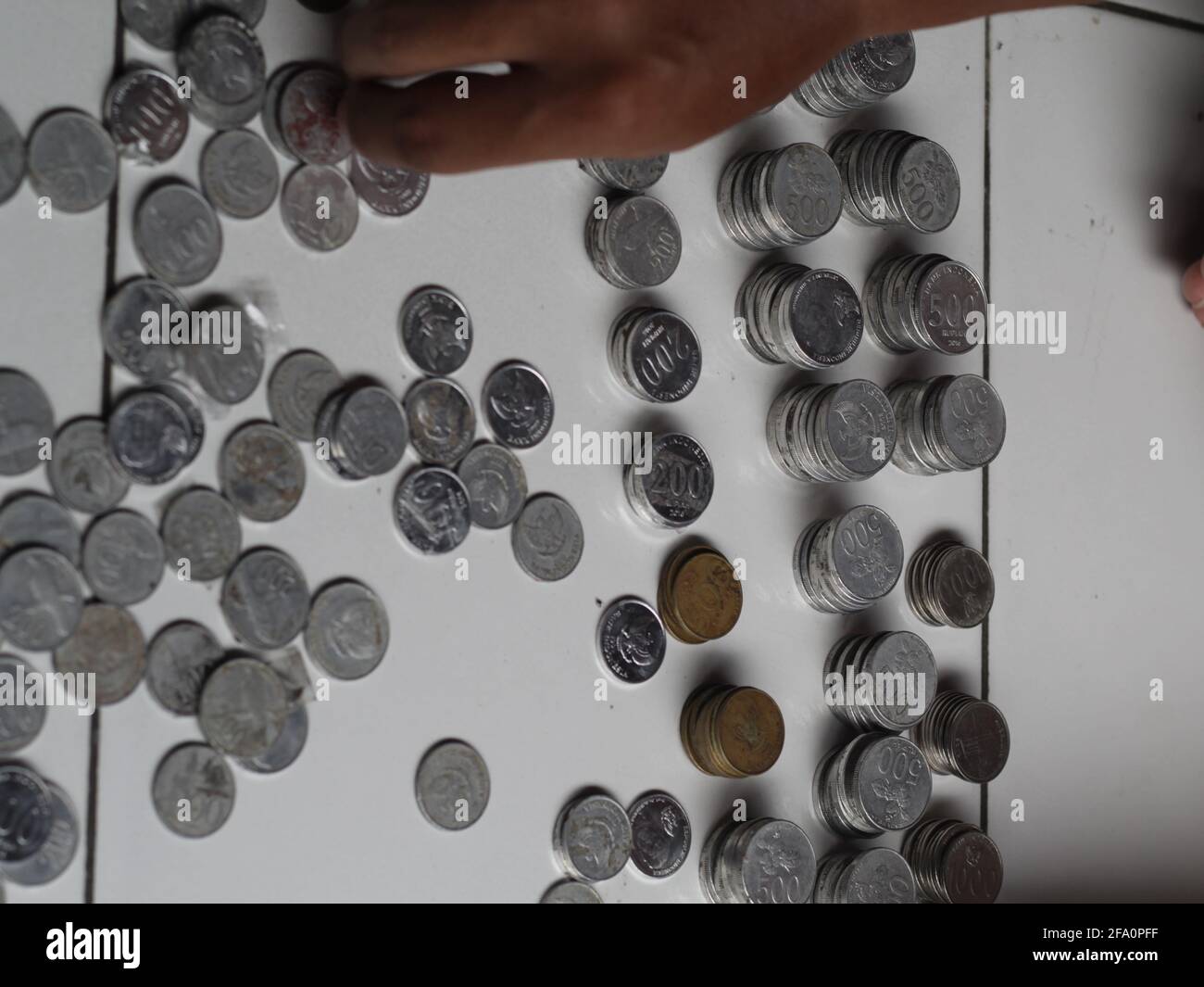 Man counting indonesian penny. Stacked Rupiah coin Stock Photo - Alamy