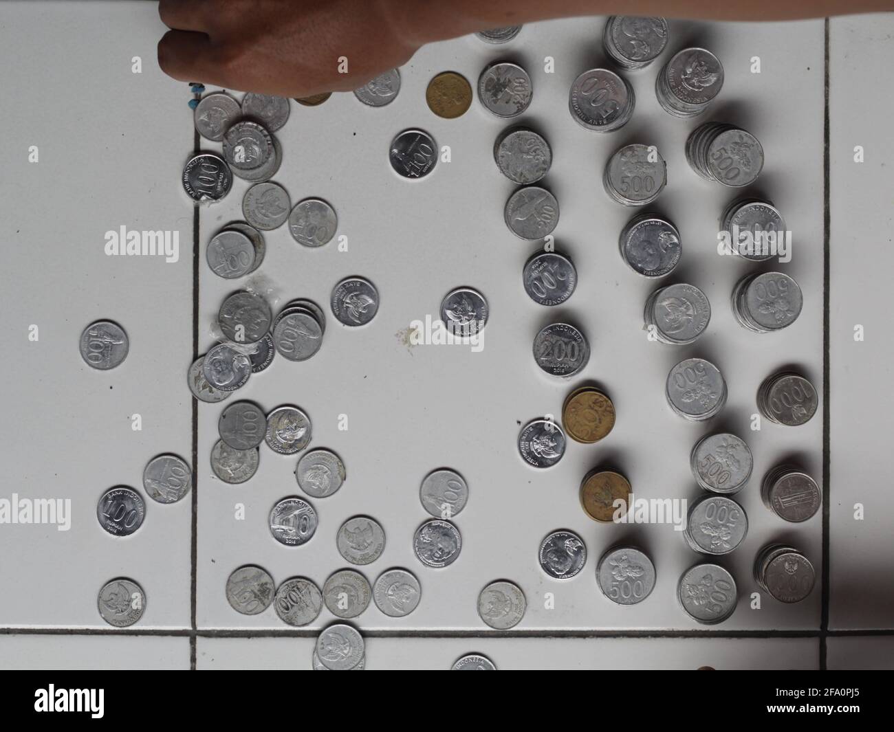 Man counting indonesian penny. Stacked Rupiah coin Stock Photo - Alamy