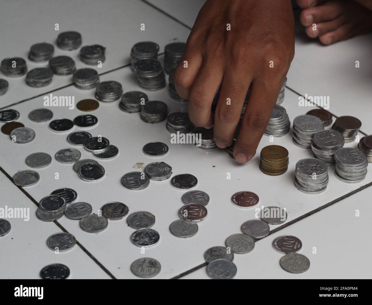Man counting indonesian penny. Stacked Rupiah coin Stock Photo - Alamy