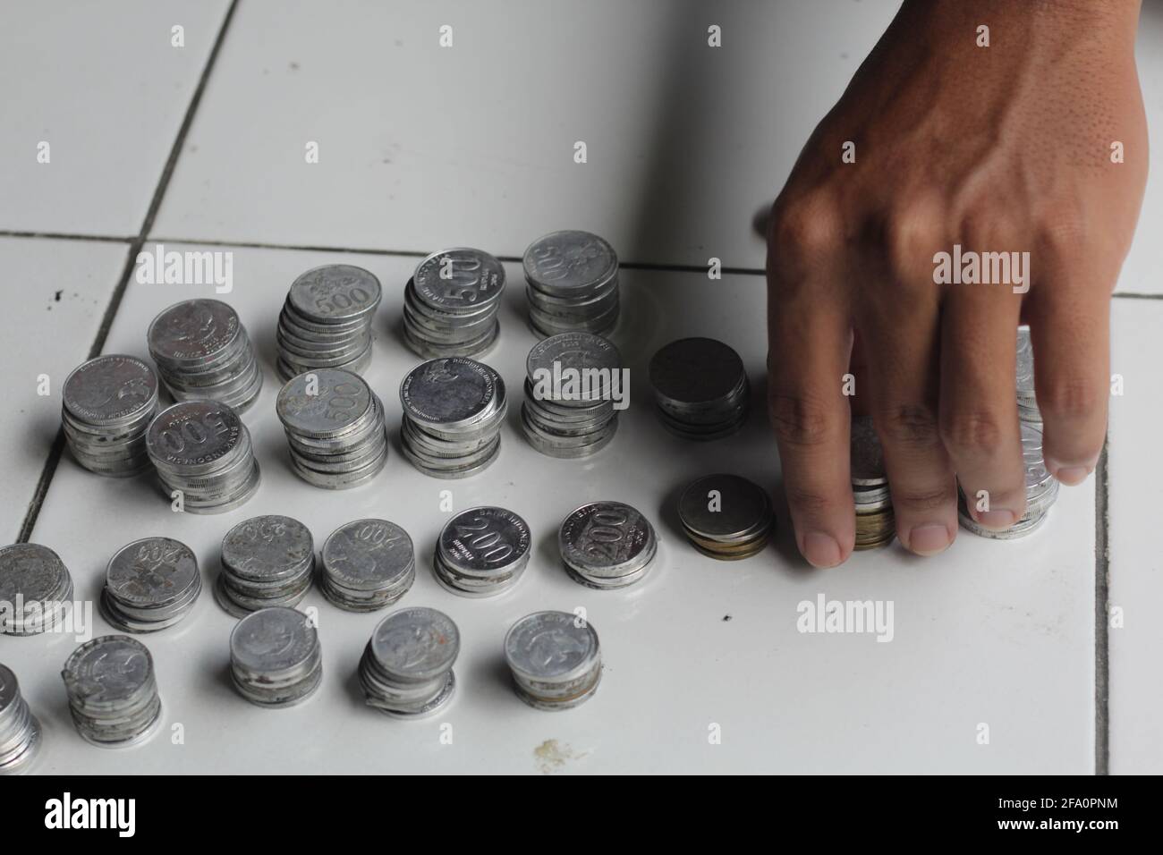 Man counting indonesian penny. Stacked Rupiah coin Stock Photo - Alamy
