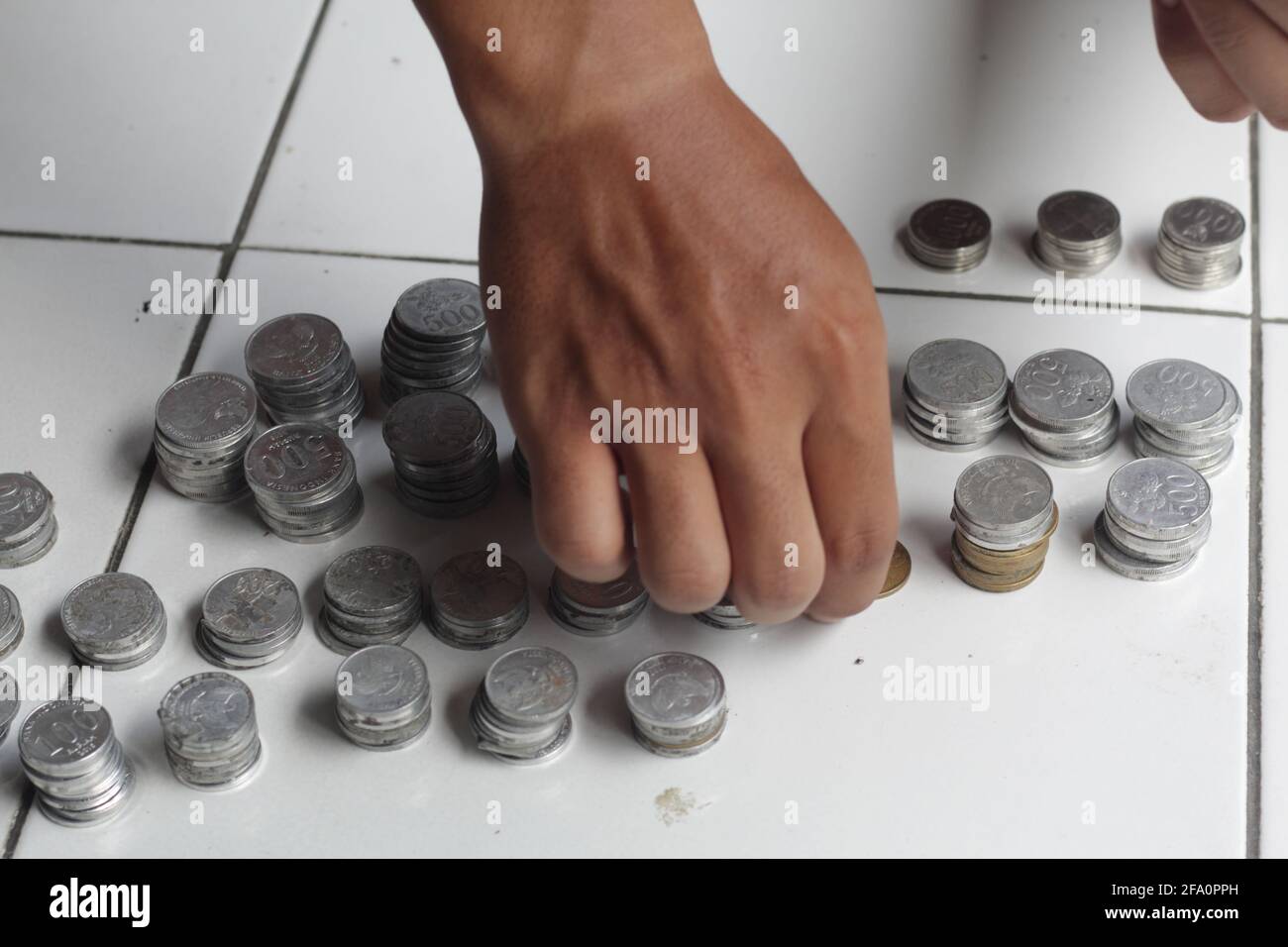 Man counting indonesian penny. Stacked Rupiah coin Stock Photo - Alamy