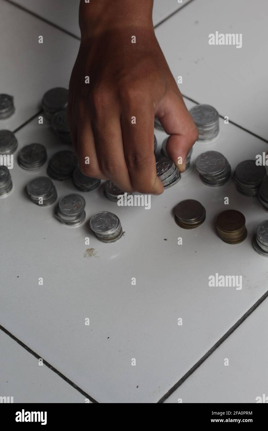 Man counting indonesian penny. Stacked Rupiah coin Stock Photo - Alamy