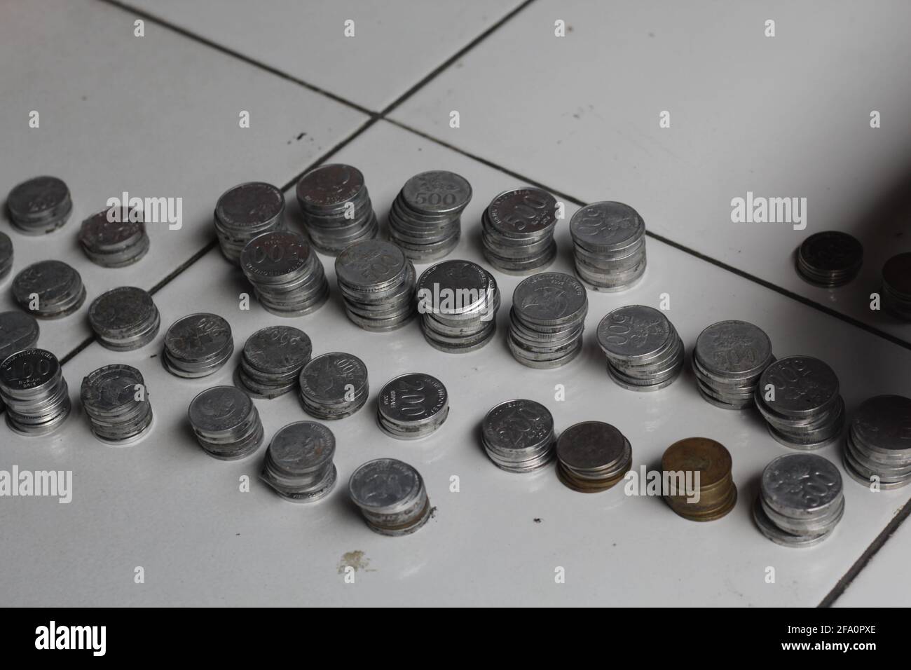 Man counting indonesian penny. Stacked Rupiah coin Stock Photo - Alamy
