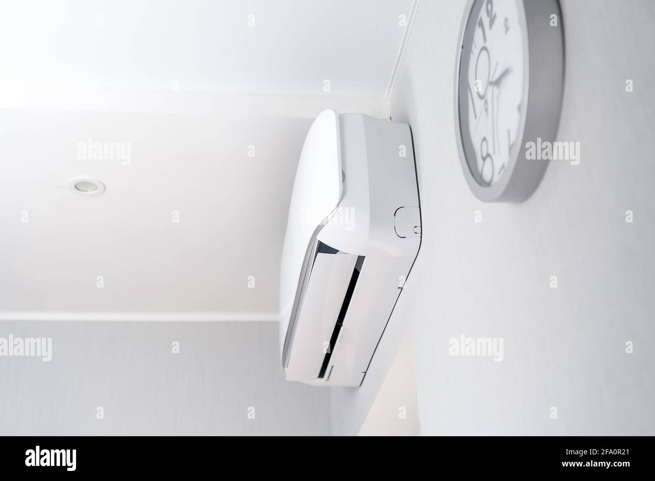 Air conditioning on a white wall with a close-up clock in a modern room ...