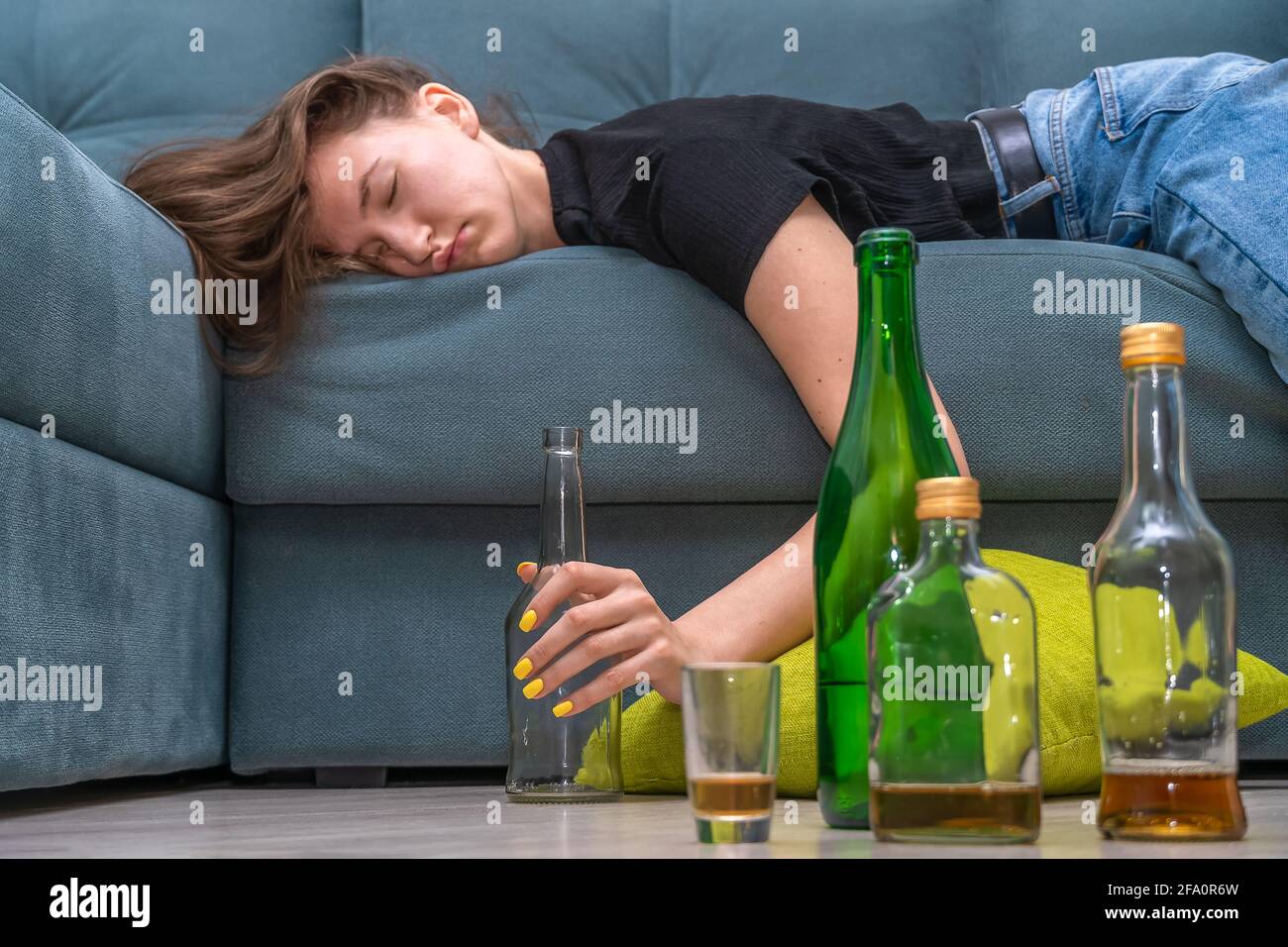 Tired young dark-haired woman lying on the couch after a party at home ...