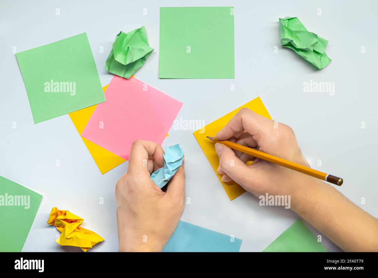 Note paper with a female hand with a pencil and crumpled paper around ...