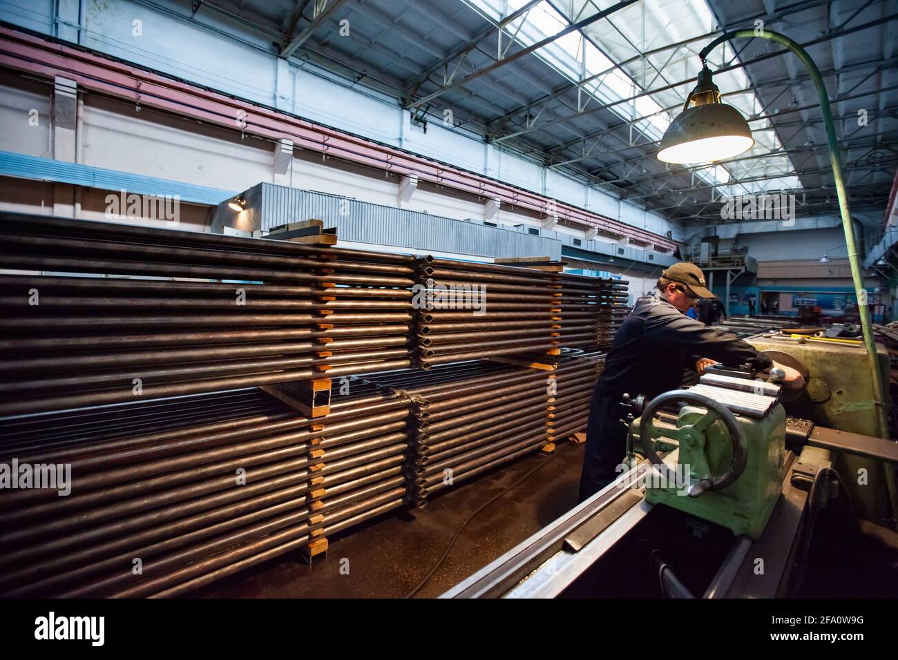 Stack of steel tubes and worker. Manufacturing water radiator system ...