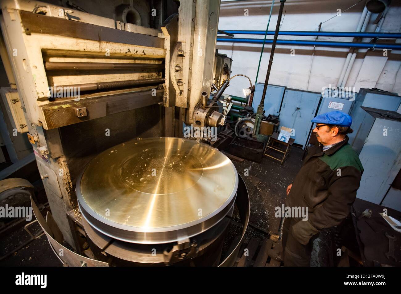 Adult turner worker and horizontal turning machine. Big round steel ...