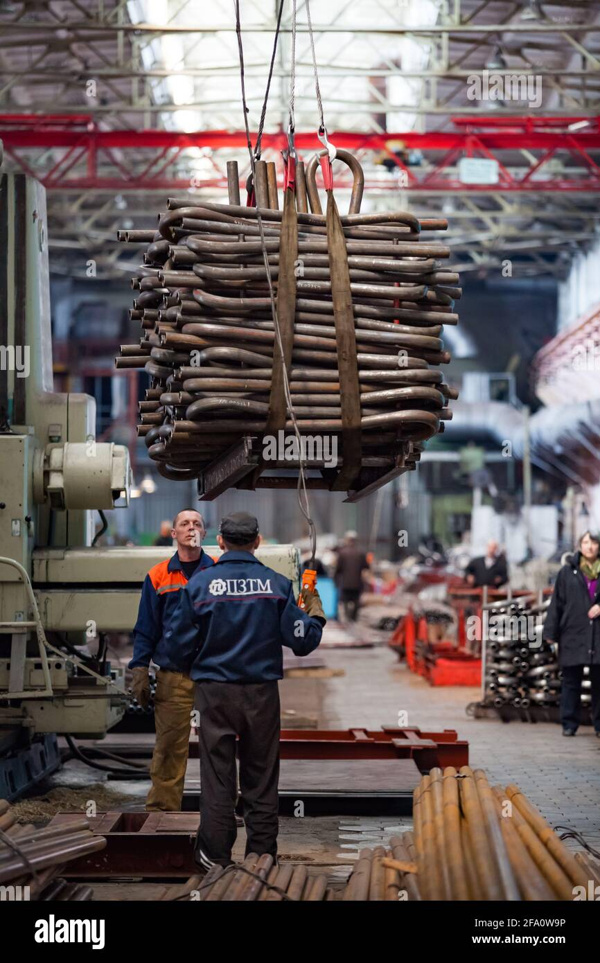 Heavy engineering plant. Workers lifting stack of pipes. Petropavlovsk ...